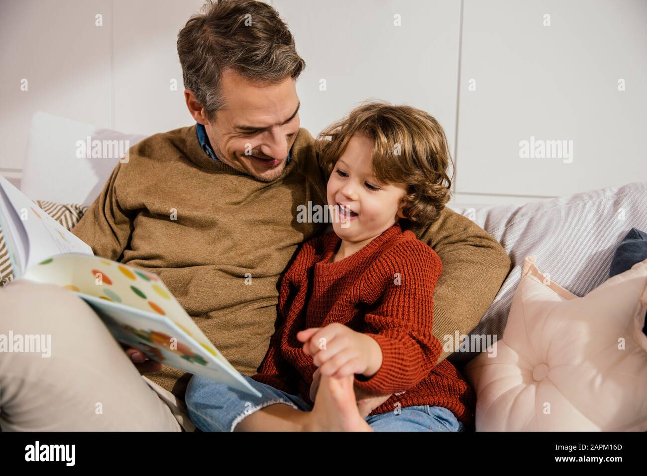 Happy father sitting with daughter on couch Stock Photo - Alamy
