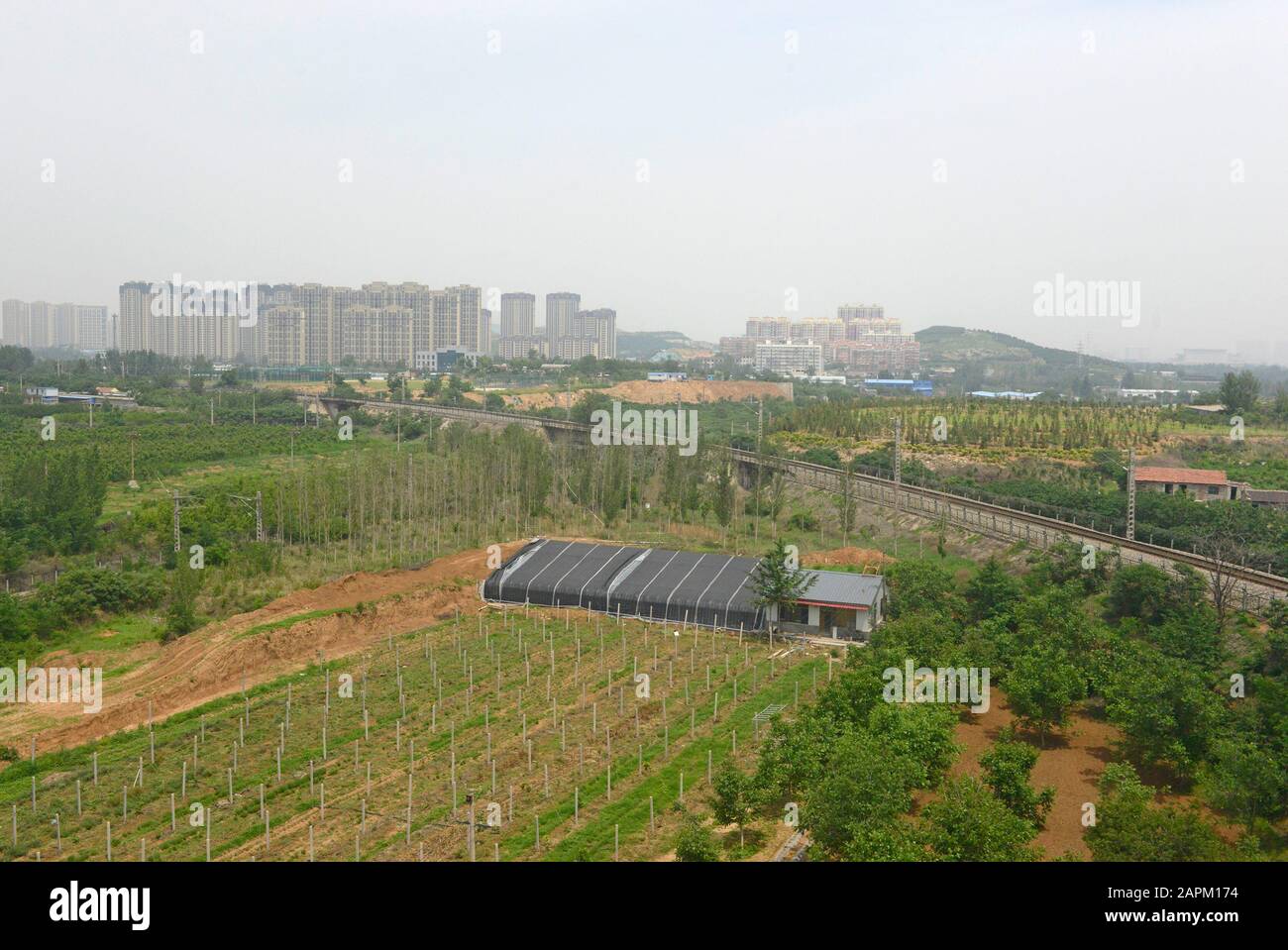 Horticultural shade house and fields of a farm by a railway line near a ...