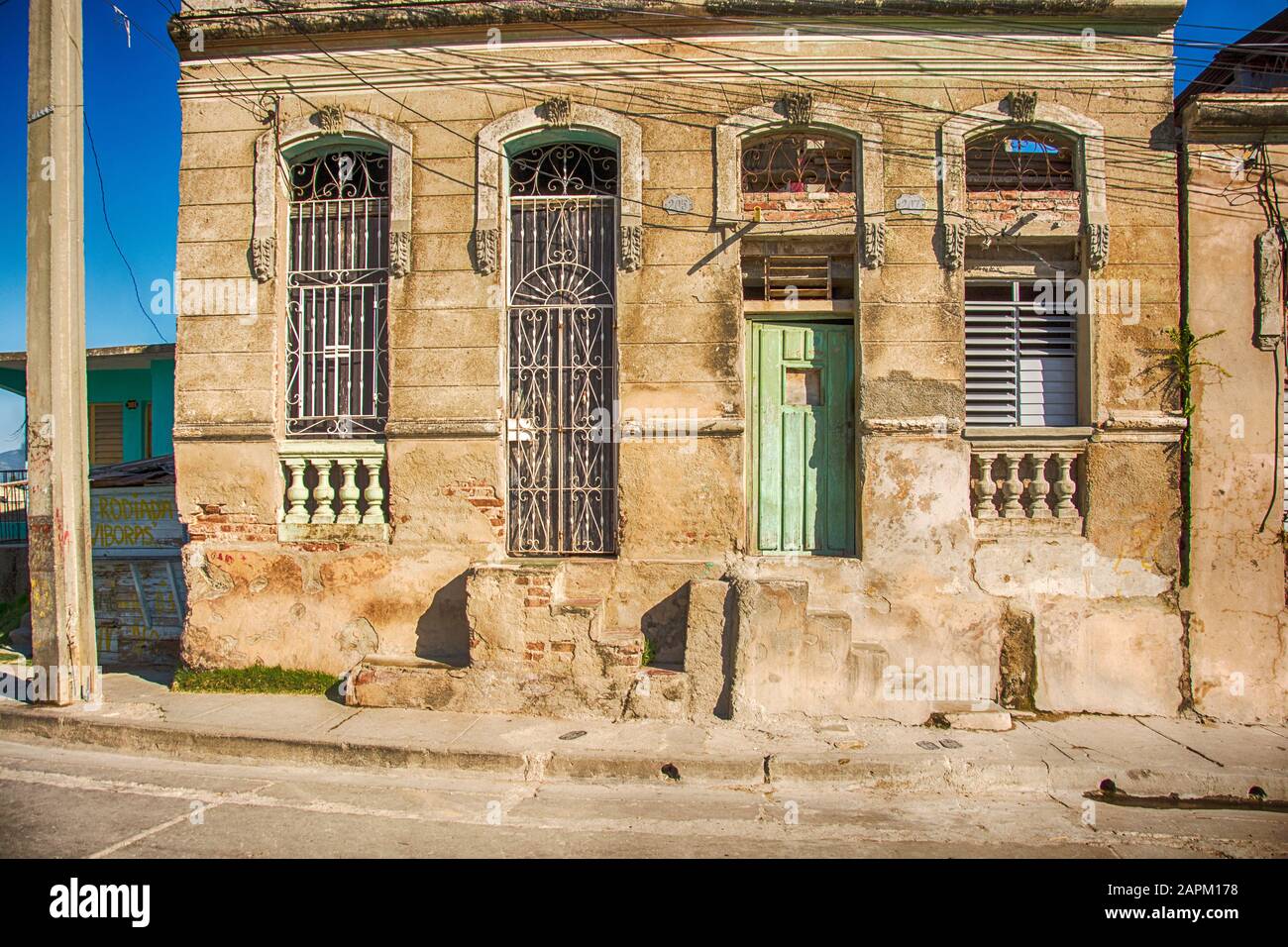 The facade of a home in Santiago de Cuba, Cuba; featuring a green door ...