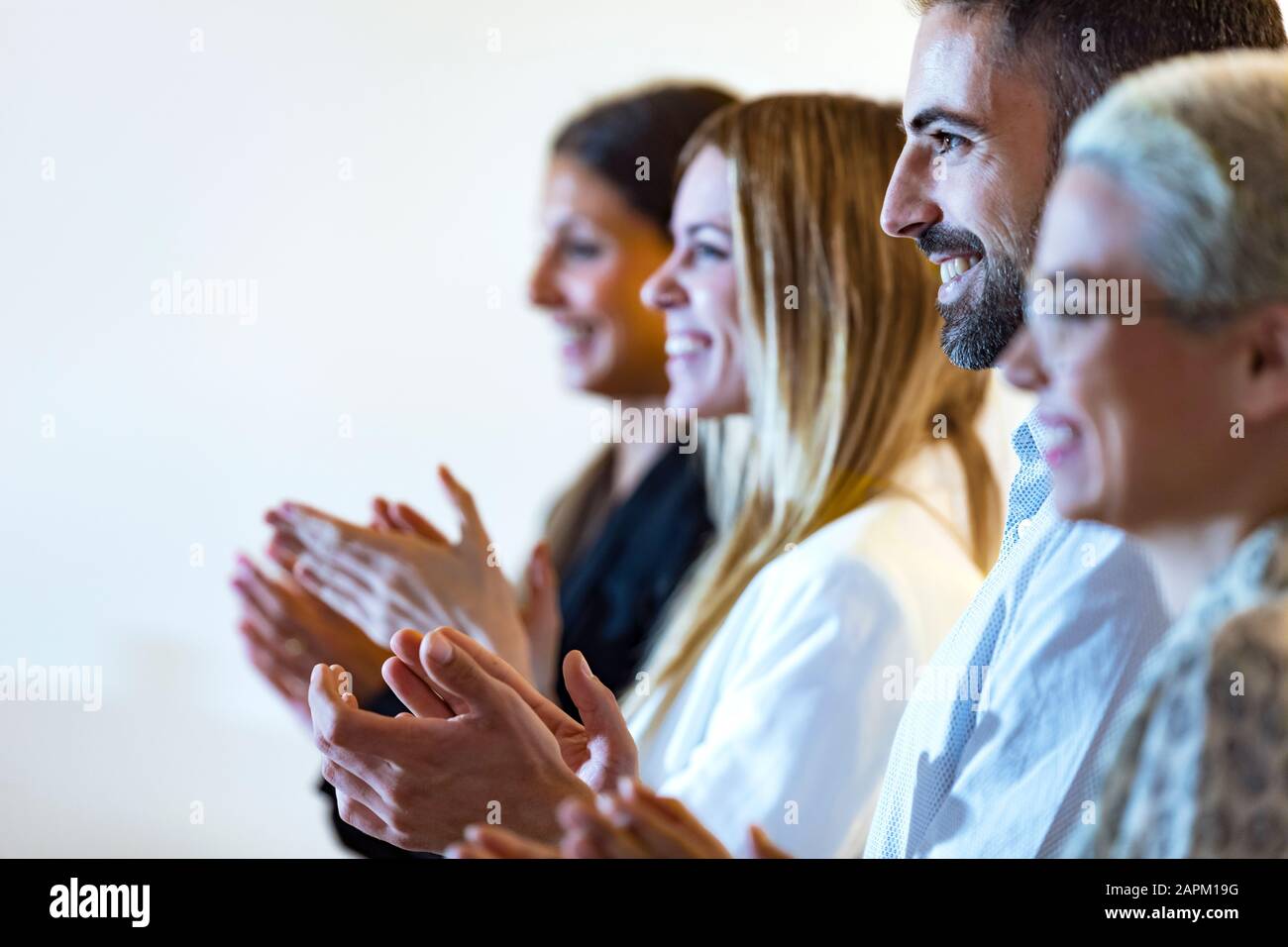 Happy business people clapping hands in office Stock Photo - Alamy