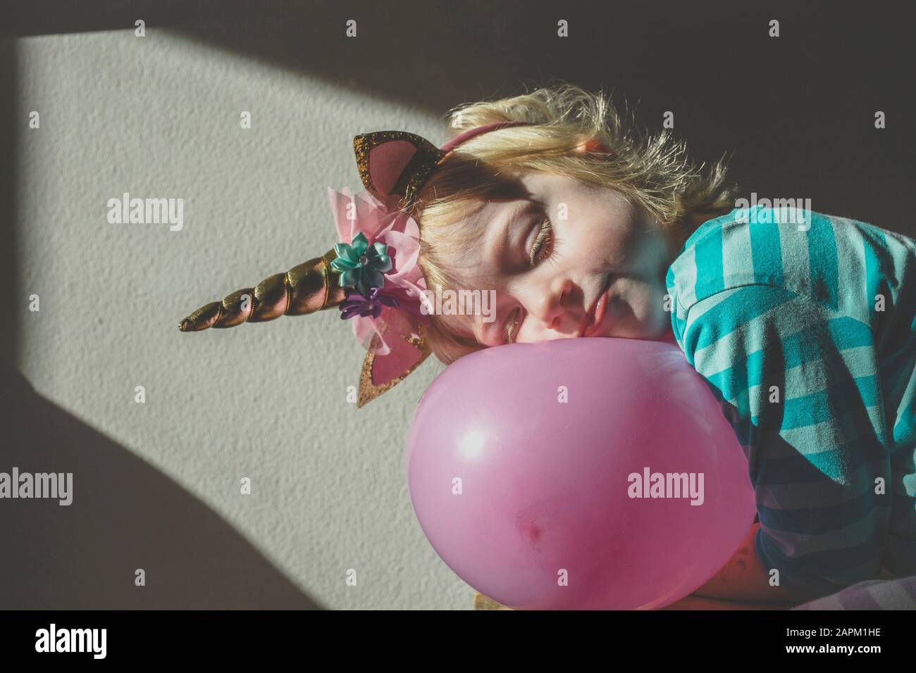 Portrait of little blond girl wearing unicorn horn leaning on pink ... Portrait of little blond girl wearing unicorn horn leaning on pink ...