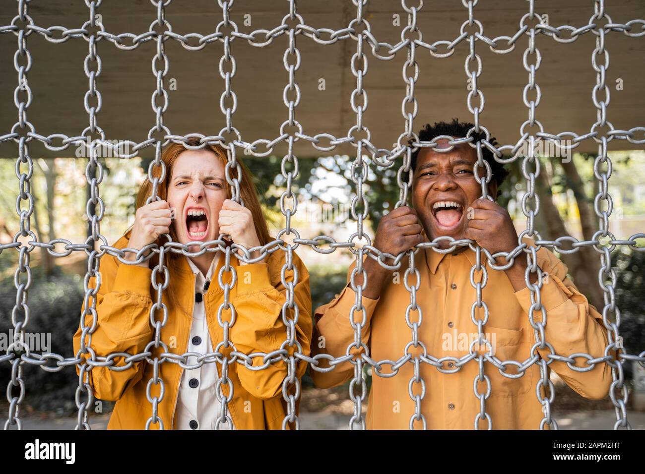 Couple screaming behind chains Stock Photo - Alamy