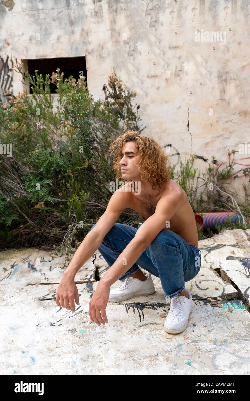 Young blond man crouching Stock Photo - Alamy