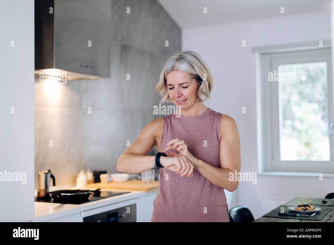 Mature woman using smartwatch in kitchen at home Stock Photo - Alamy