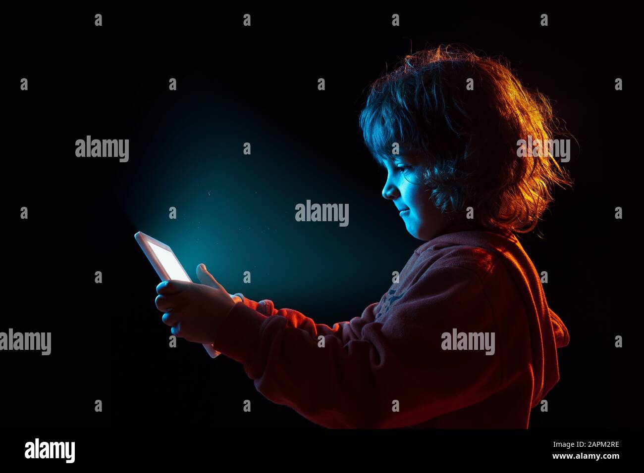 Vlogging with tablet, playing. Caucasian boy's portrait on dark studio ...