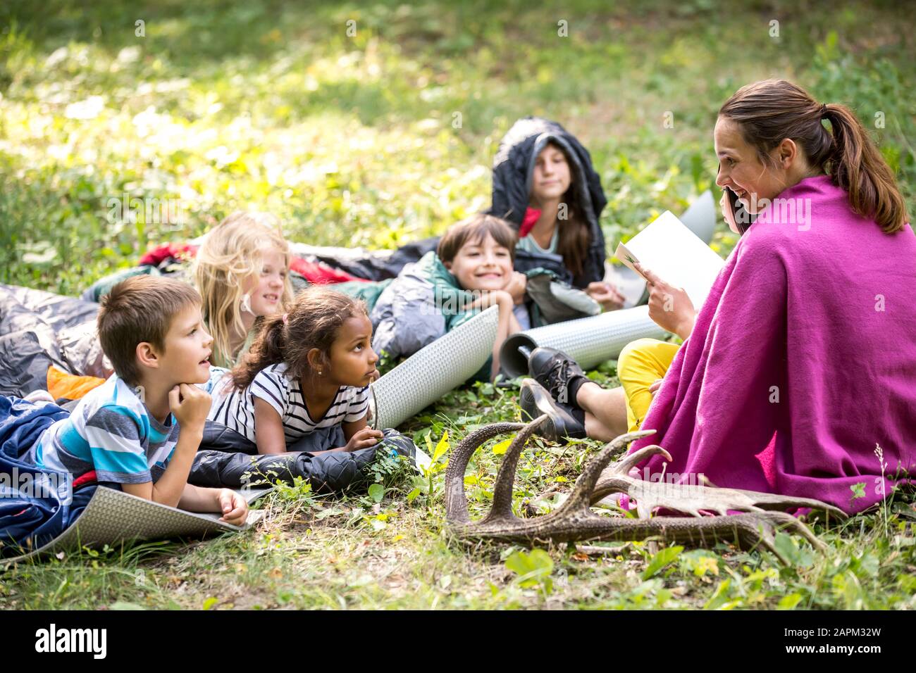 Teacher reading story to school children, camping in the forest Stock ...