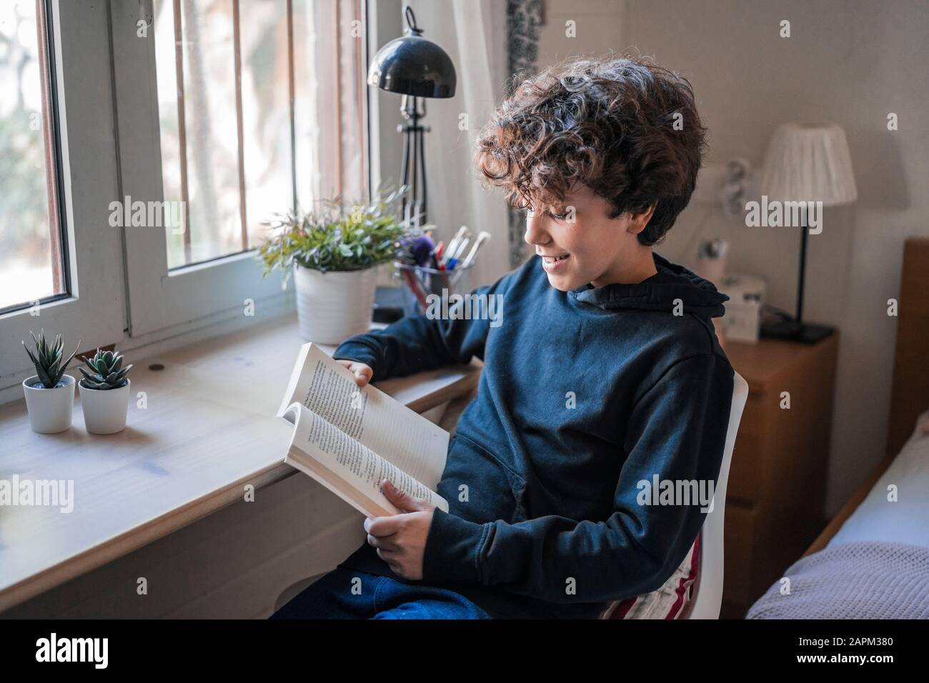 Smiling boy reading book at home Stock Photo - Alamy