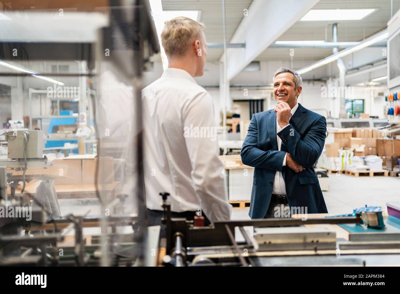 Two businessmen talking in a factory Stock Photo - Alamy
