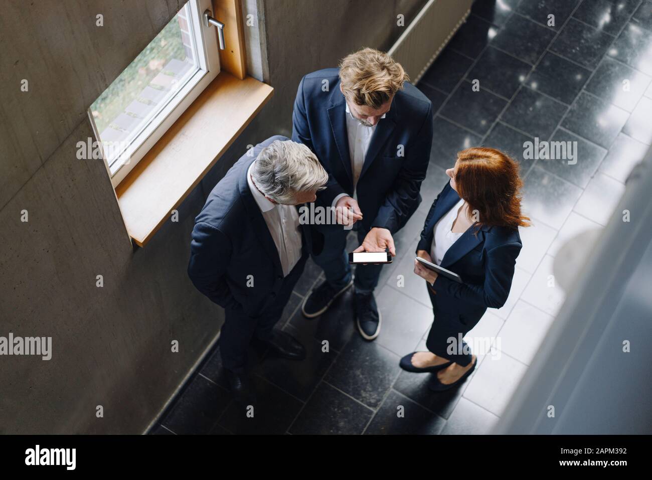 Business people with smartphone talking in modern office building Stock ...