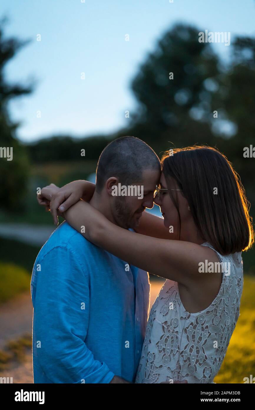 Couple in love hugging outdoors at dusk Stock Photo - Alamy