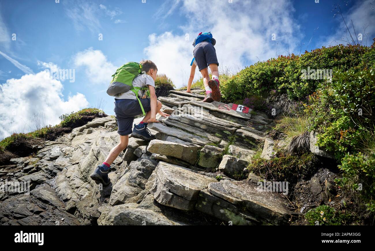 Boy and girl climbing up rock in the mountains, Passeier Valley, South ...