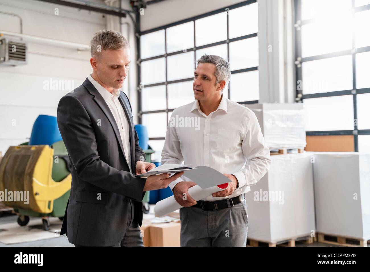 Two businessmen talking in a factory Stock Photo - Alamy