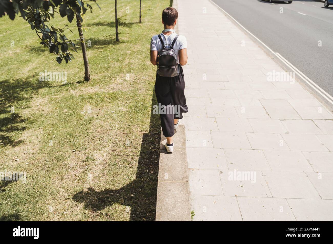 Back view of woman with backpack balancing on a wall Stock Photo - Alamy