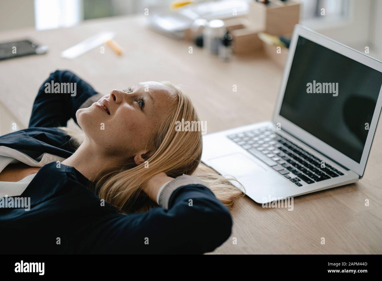 Young businesswoman having a break in office lying on desk Stock Photo ...