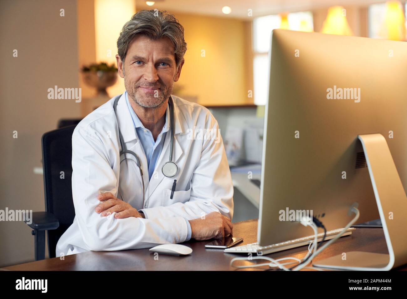 Portrait of confident doctor at desk in his medical practice Stock ...