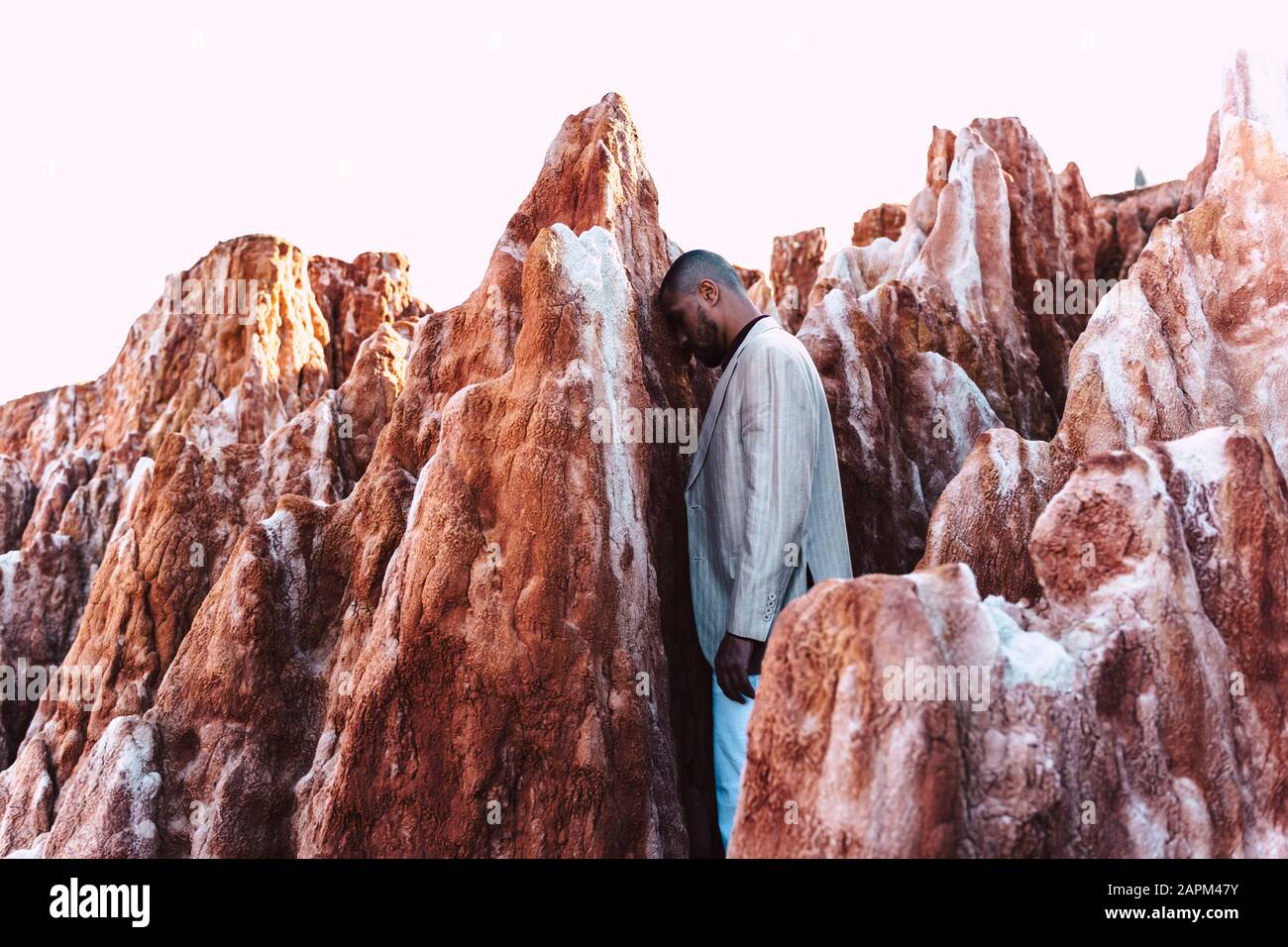 Desperate young man standing with head against rock Stock Photo - Alamy