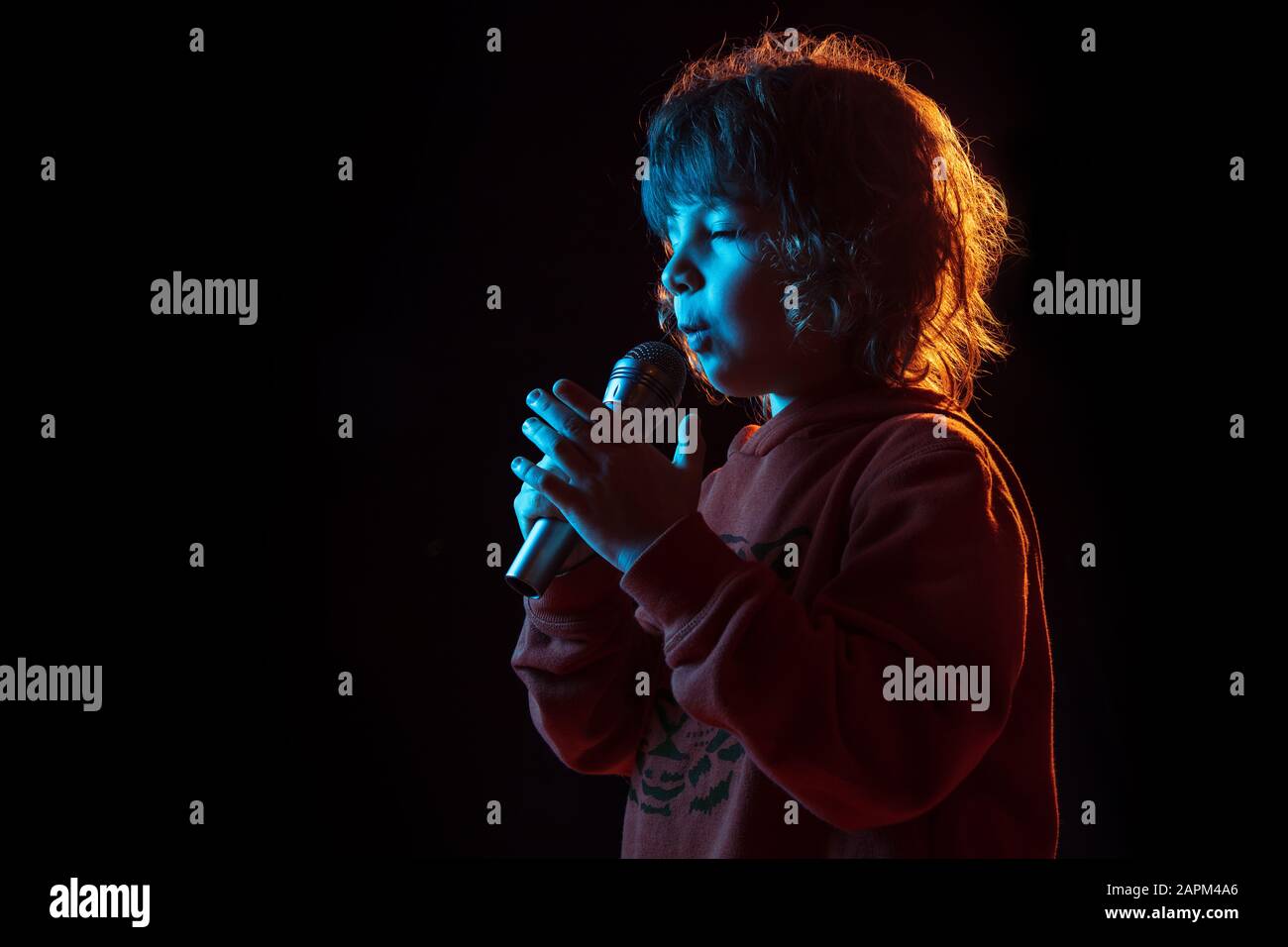 Singing like celebrity, rockstar. Caucasian boy's portrait on dark ...