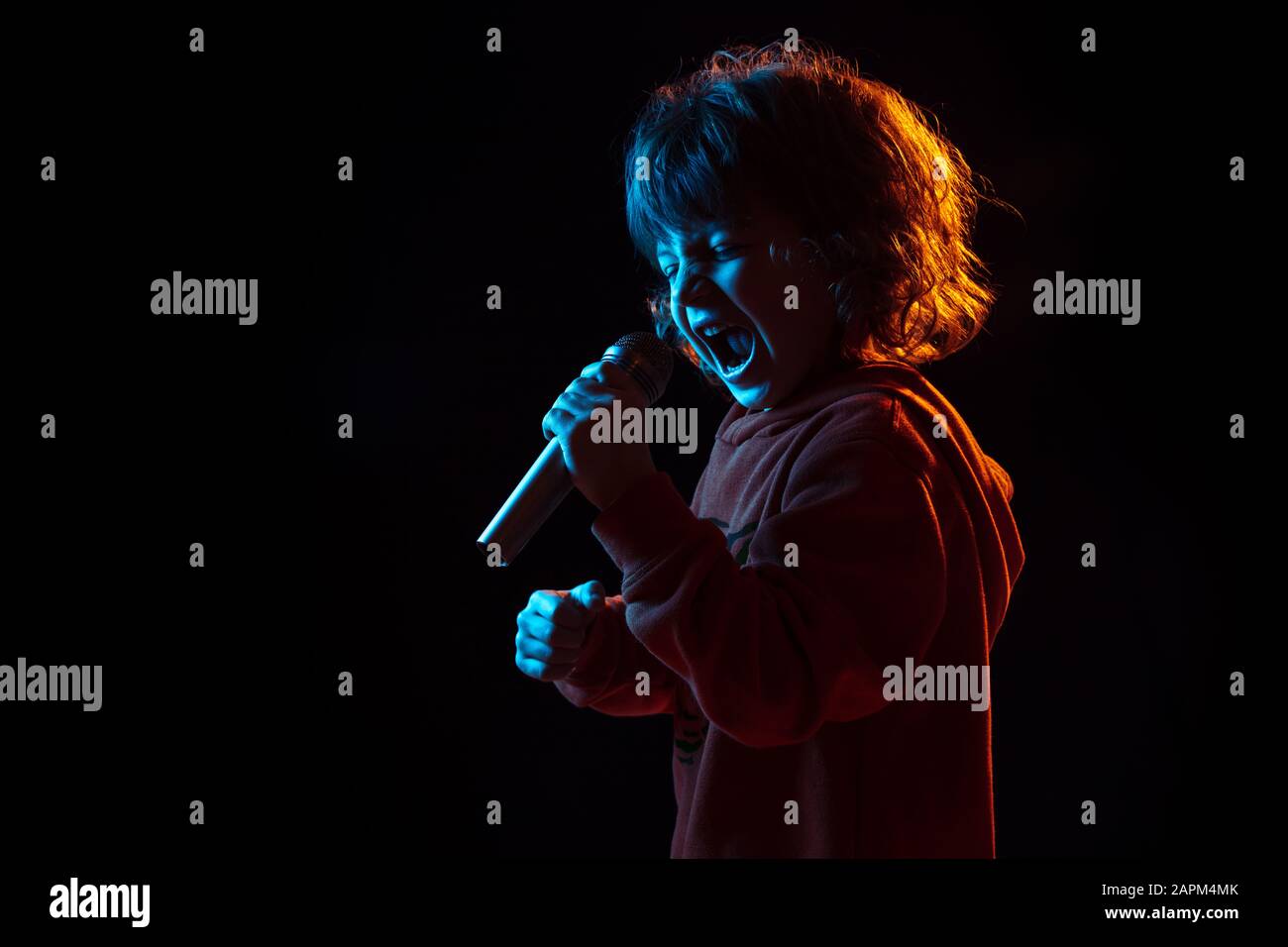 Singing like celebrity, rockstar. Caucasian boy's portrait on dark ...