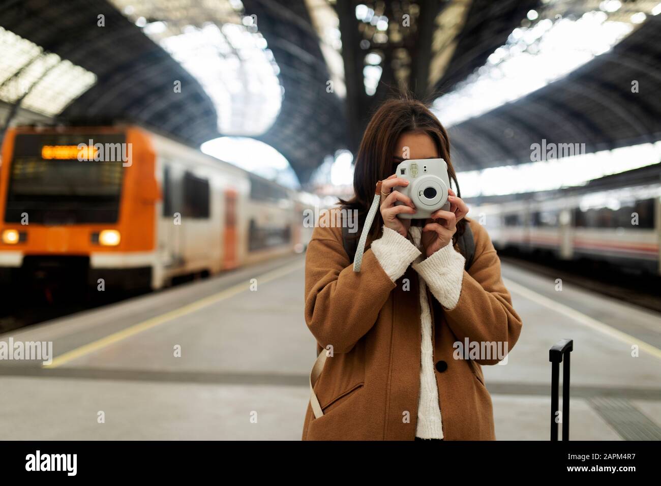 Young woman taking picture with camera at the train station Stock Photo ...