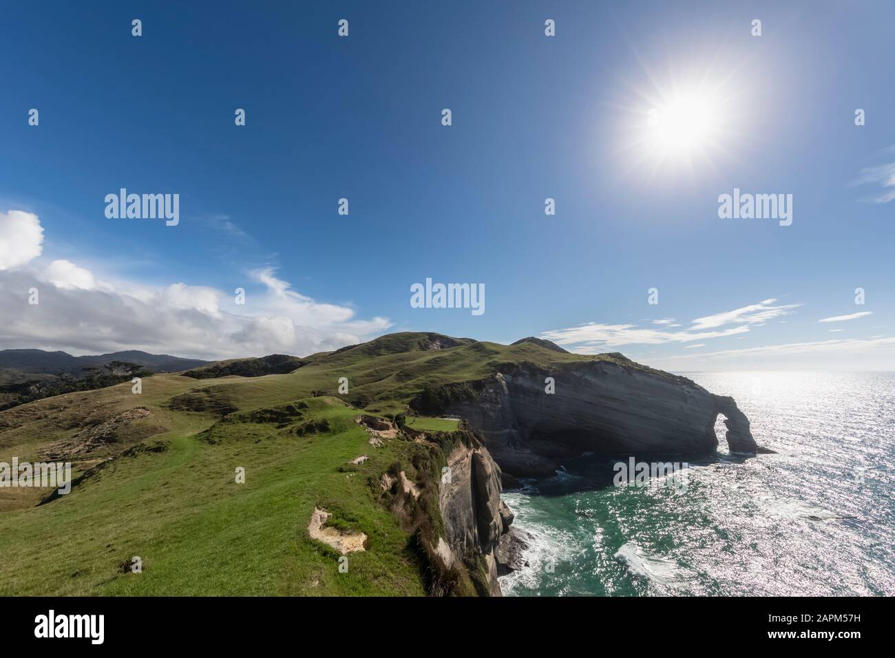 New Zealand, Sun shining over cliffs and natural arch of Cape Farewell ...