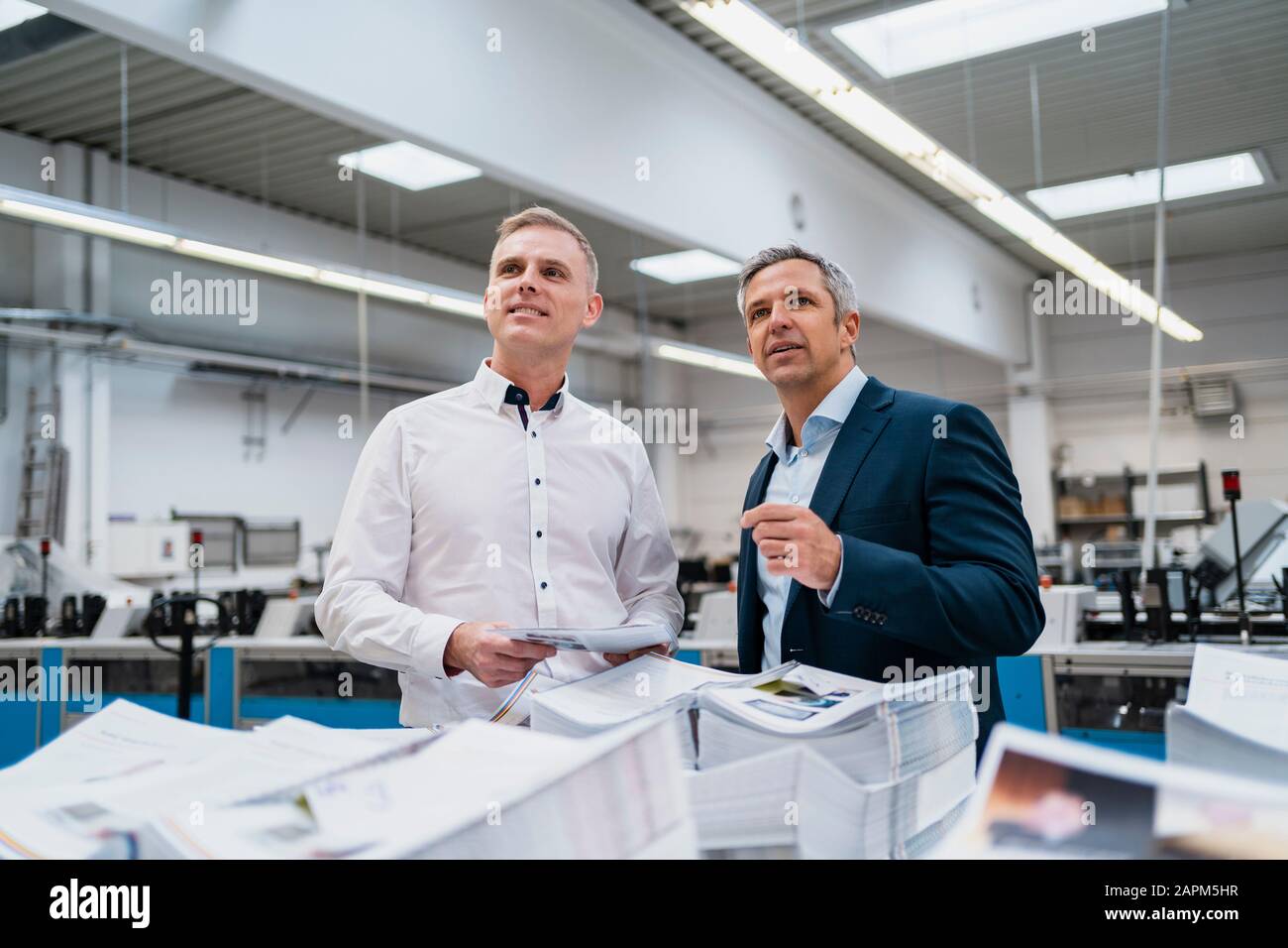 Two businessmen talking in a factory Stock Photo - Alamy
