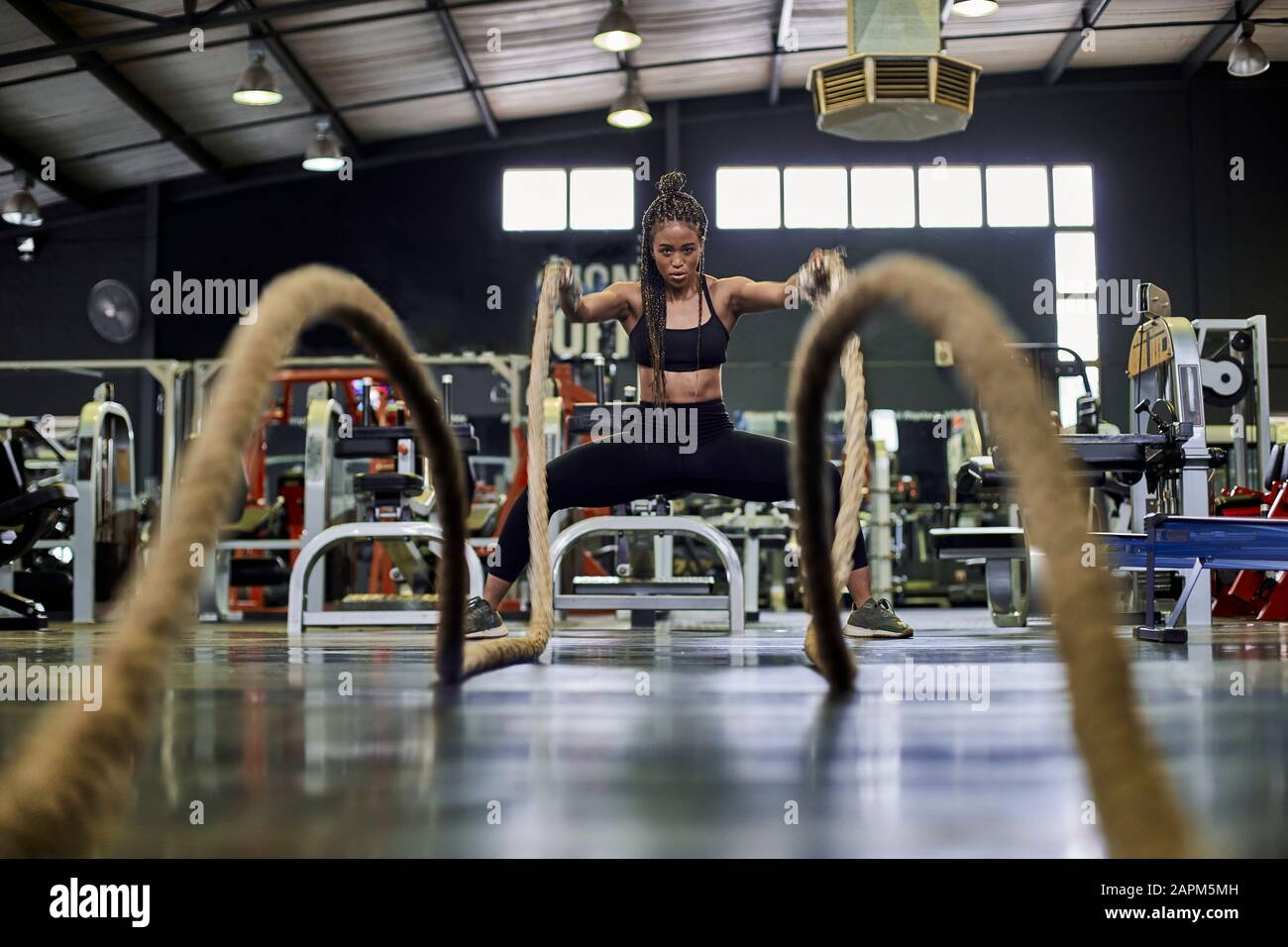 Female athlete doing strength training with heavy ropes in gym Stock ...