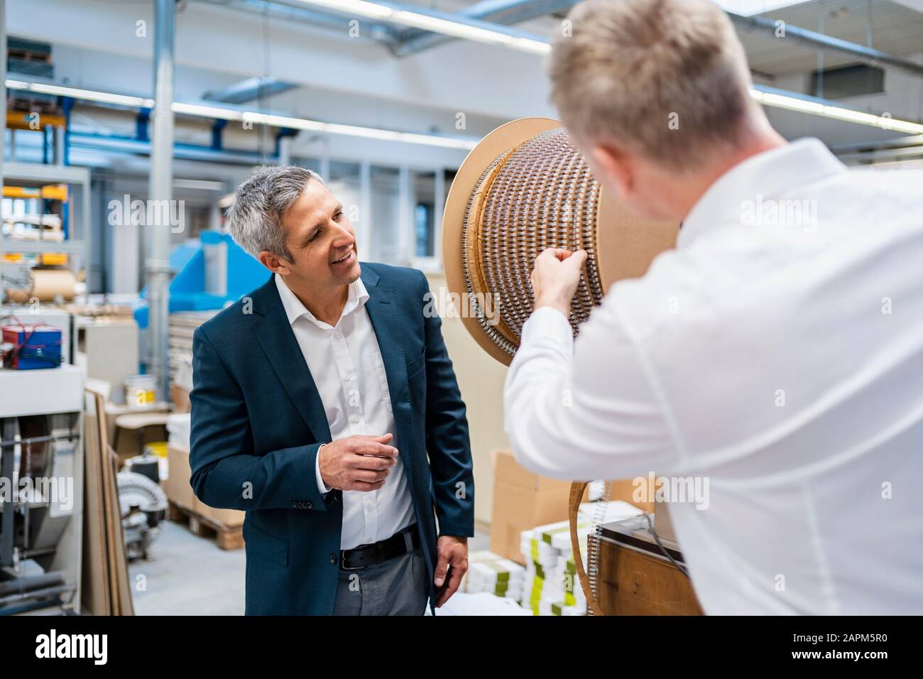 Two businessmen talking in a factory Stock Photo - Alamy