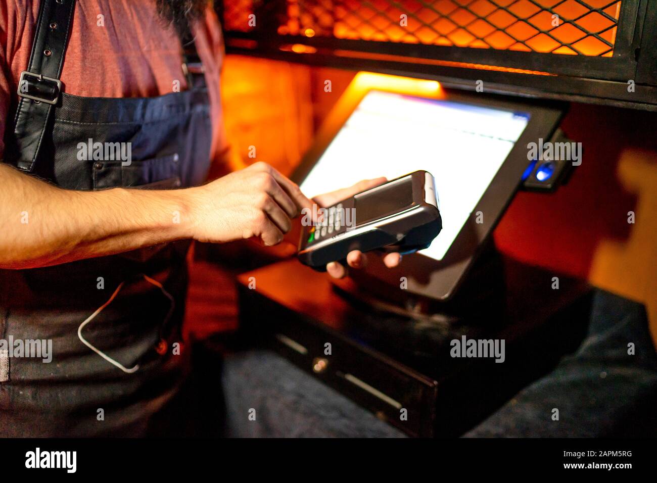 Young man, working in bar, using card reader Stock Photo - Alamy
