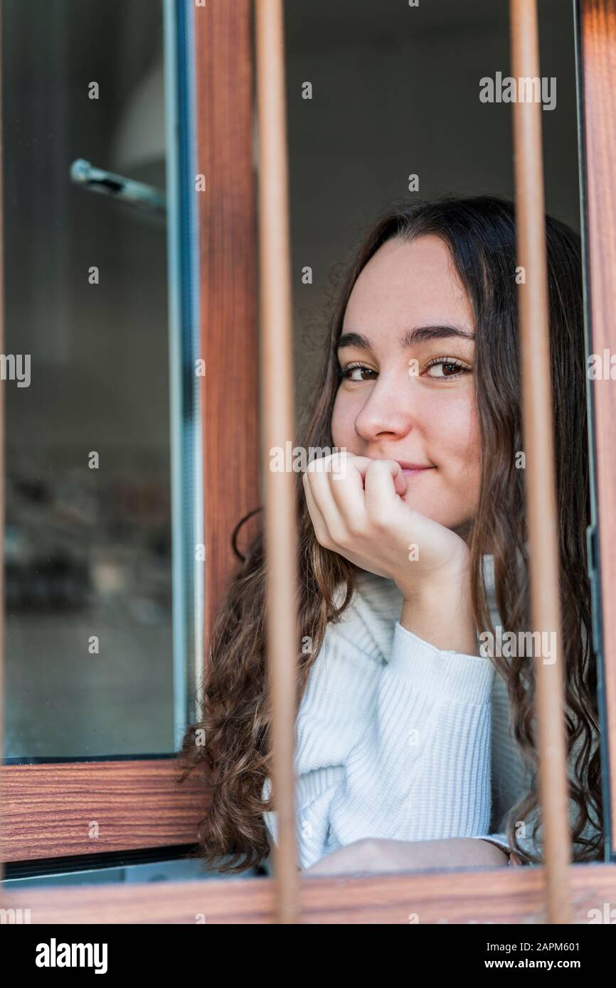 Portrait of smiling teenage girl looking out of window Stock Photo - Alamy
