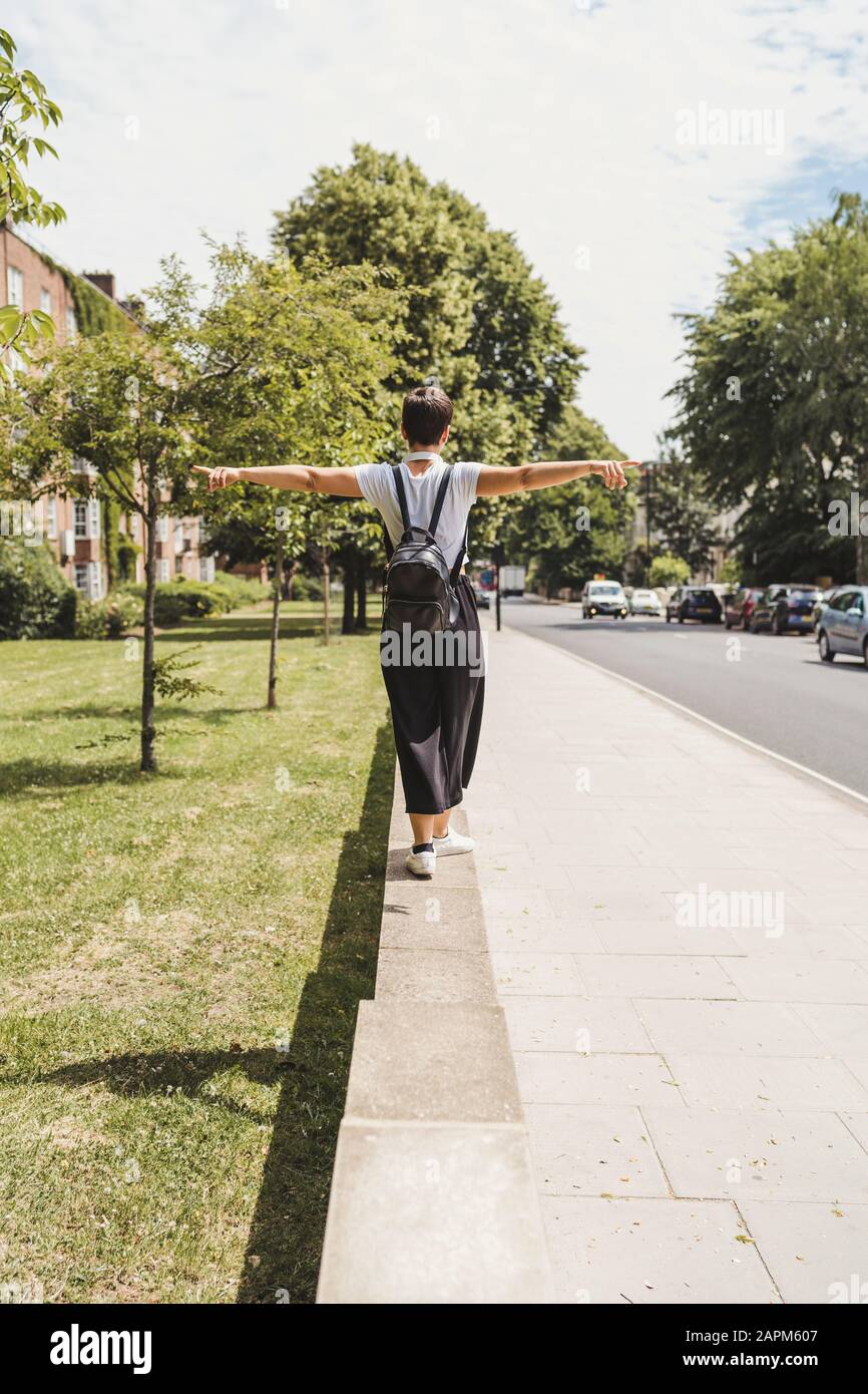Back view of woman with backpack balancing on a wall Stock Photo - Alamy