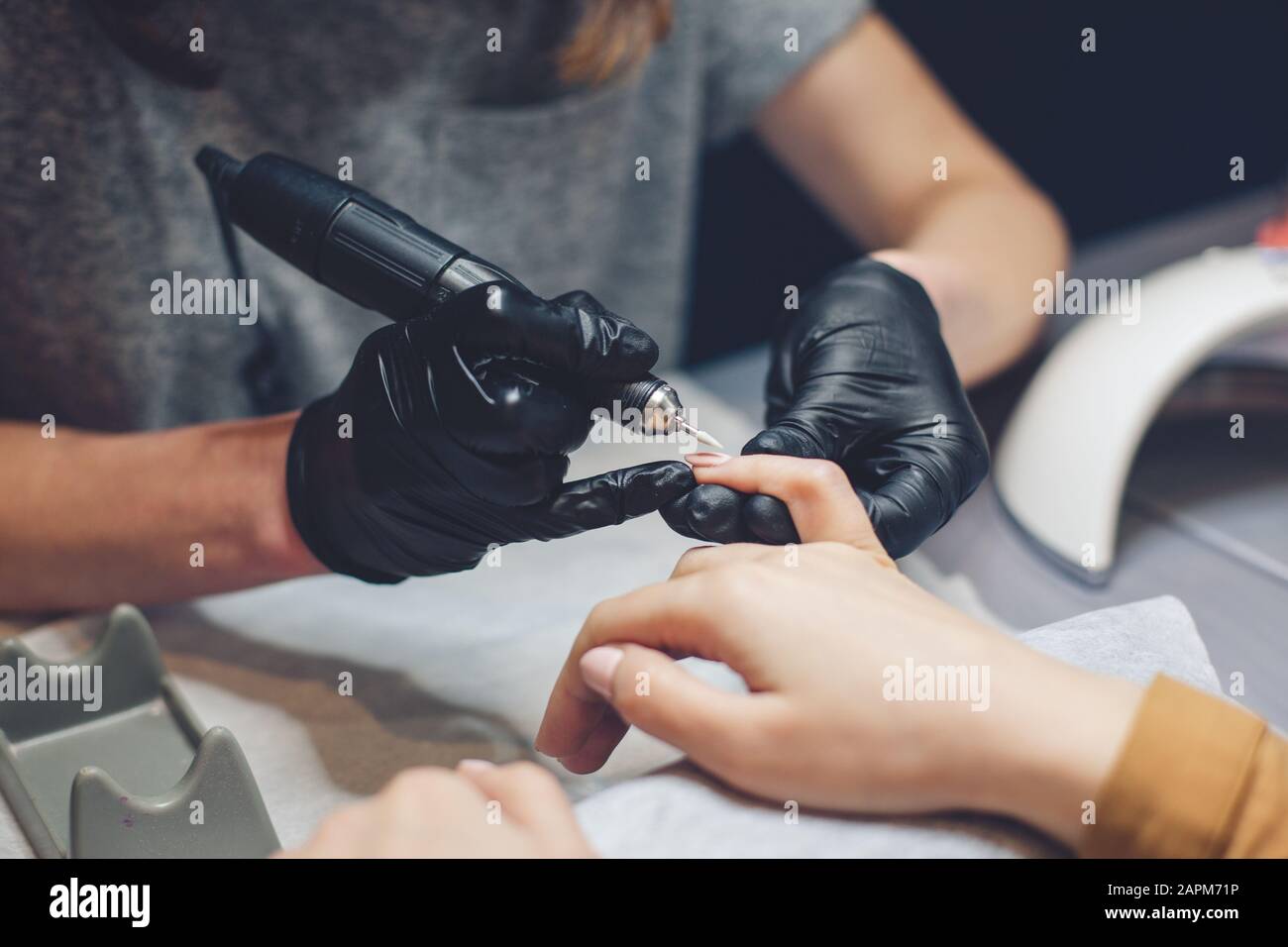 Close-up professional beautician hands working with electric drill file ...