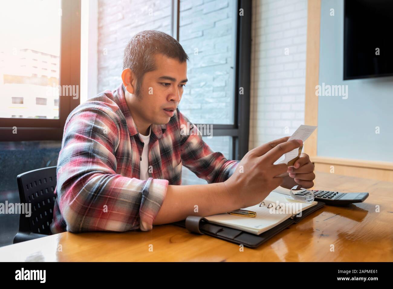 Asian man calculating expences, trying to solve budget problems ...