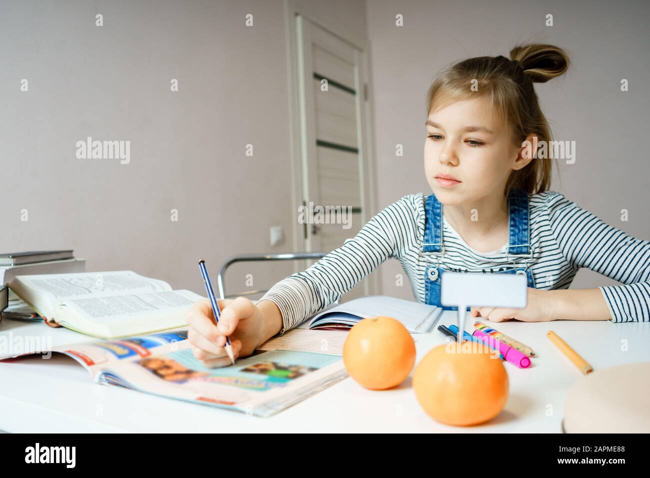 Teenage girl doing homework at table Stock Photo - Alamy