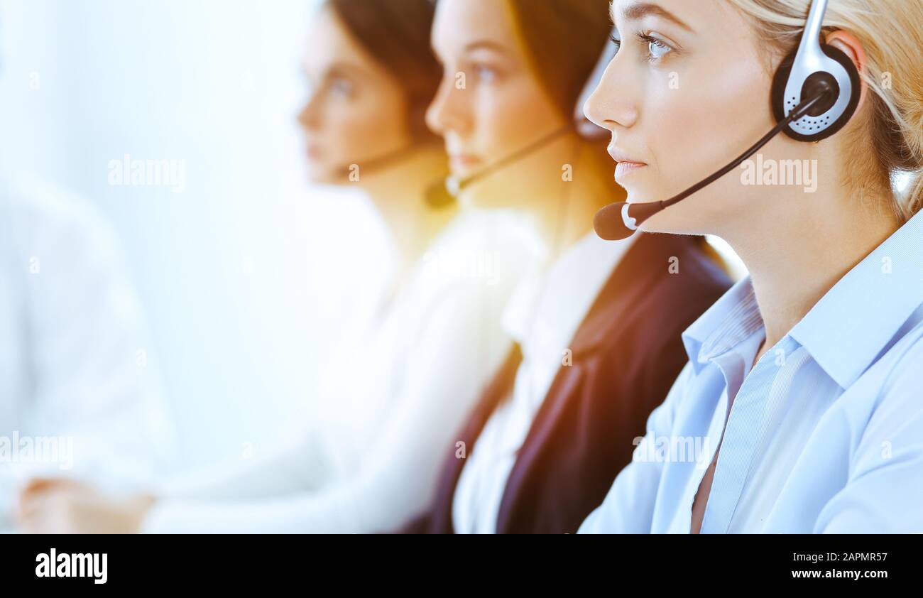 Group of diverse phone operators at work in sunny office. Handsome ...