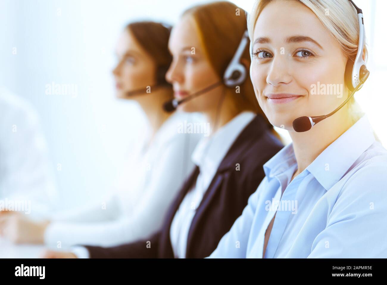 Group of diverse phone operators at work in sunny office. Handsome ...