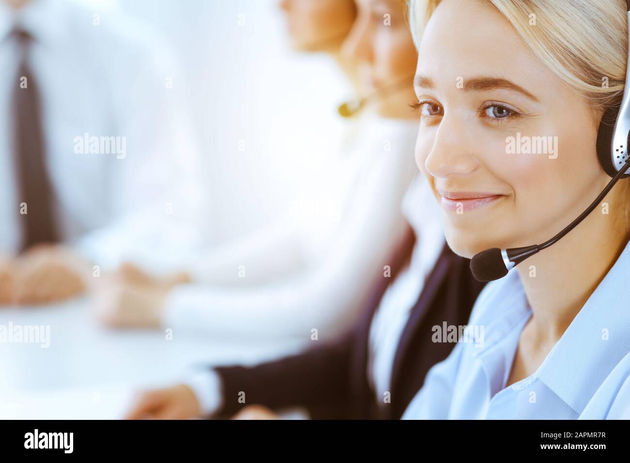 Group of diverse phone operators at work in sunny office. Handsome ...
