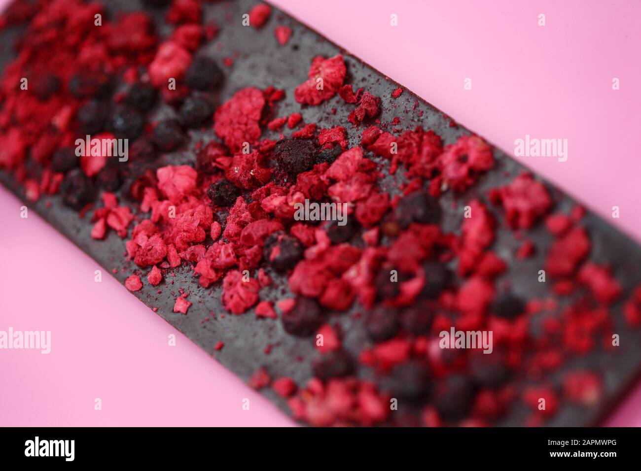 Black low calorie chocolate with dried red berries on bright pink ...