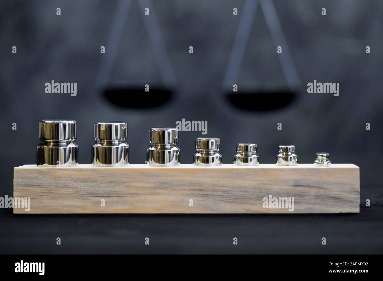 Shiny metal weight weights of various weights in a wooden stand on the ...