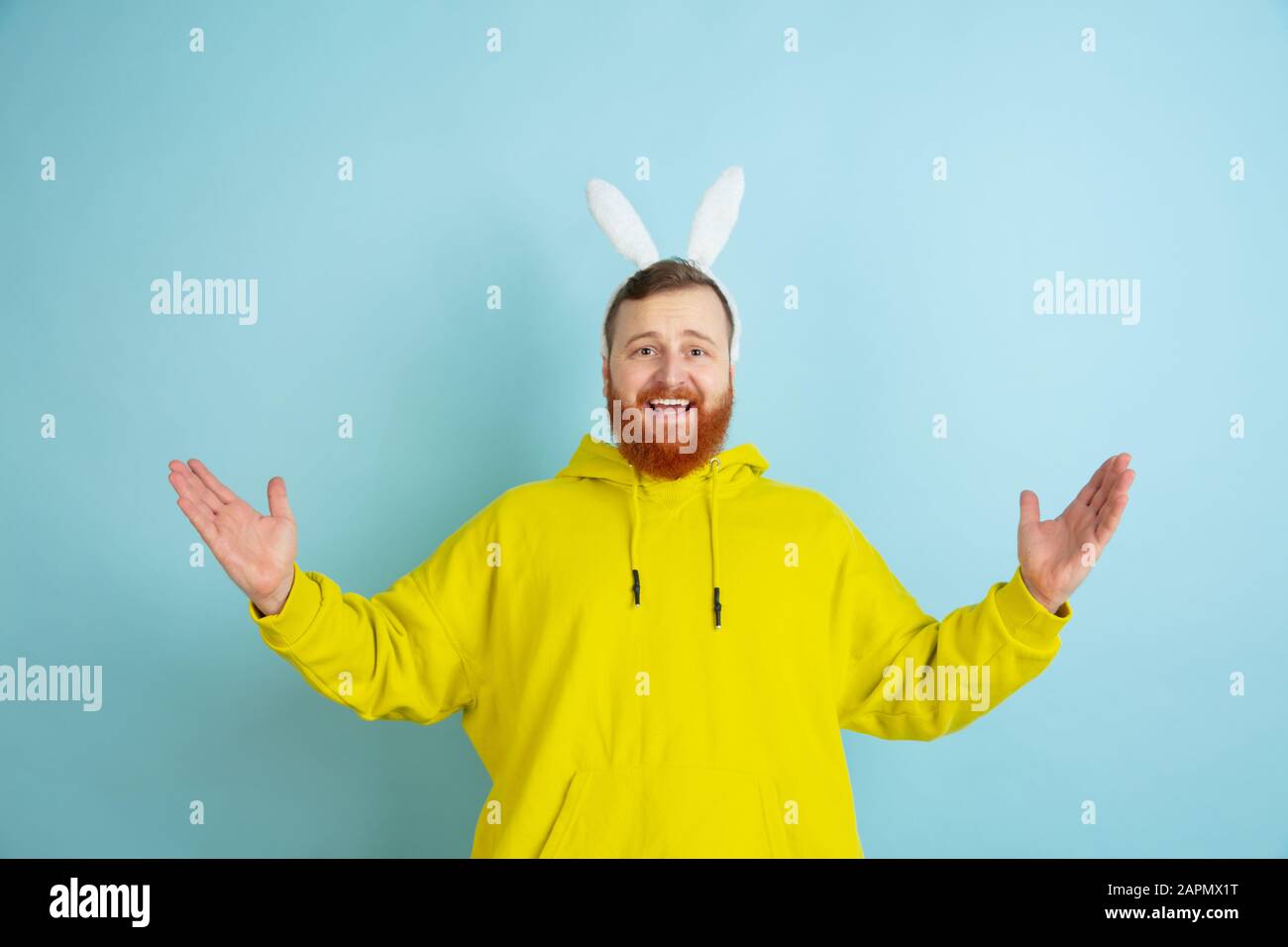 Greeting, inviting. Caucasian man as an Easter bunny with bright casual ...