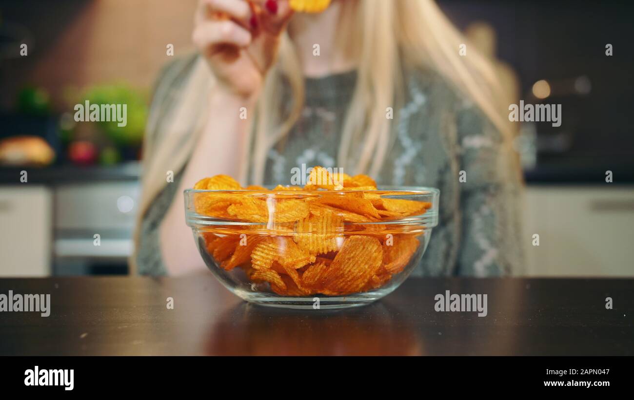 Close-up shot of woman eating potato chips. Beautiful young female ...