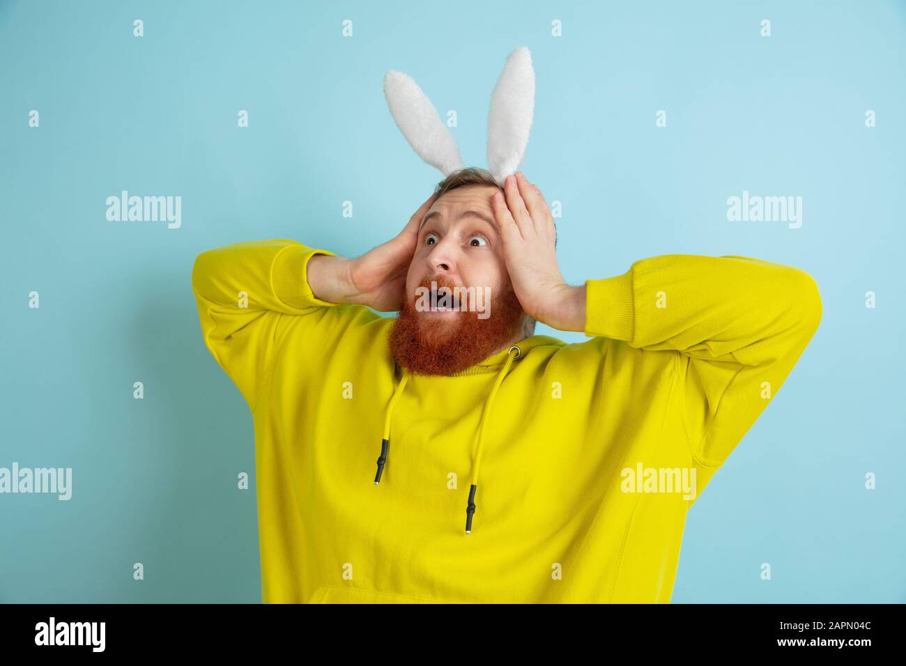 Shocked, astonished. Caucasian man as an Easter bunny with bright ...