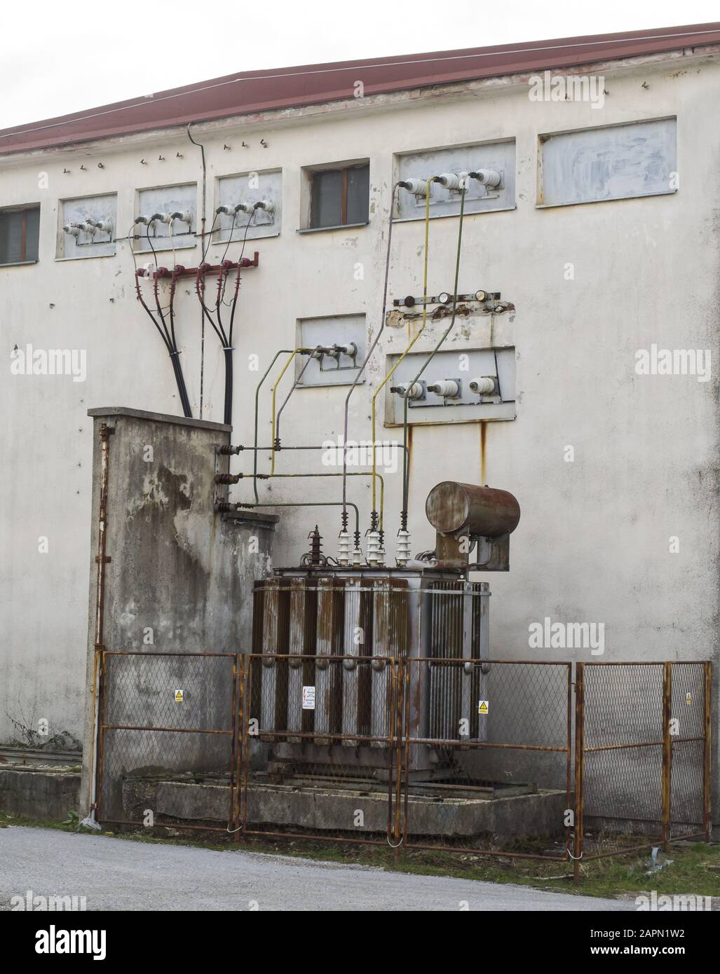 Full shot of a transformer system behind a building with wires and ...
