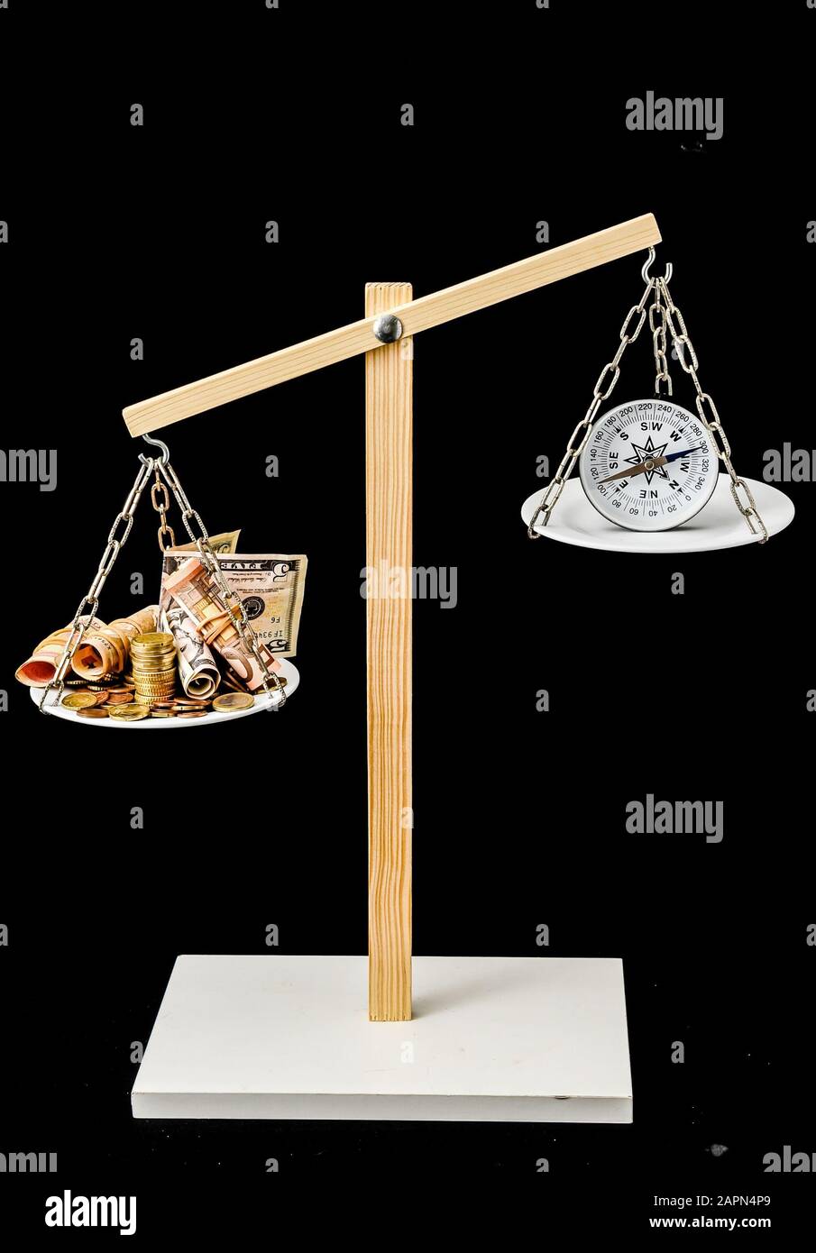 Vertical shot of a balancing scale balances money and compass with a ...