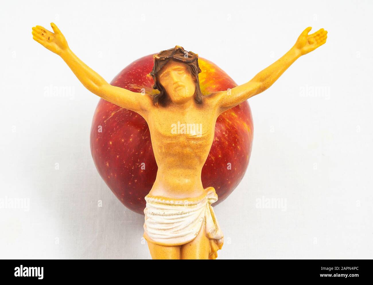 High angle shot of a figurine of Jesus laid on the top of a red apple ...