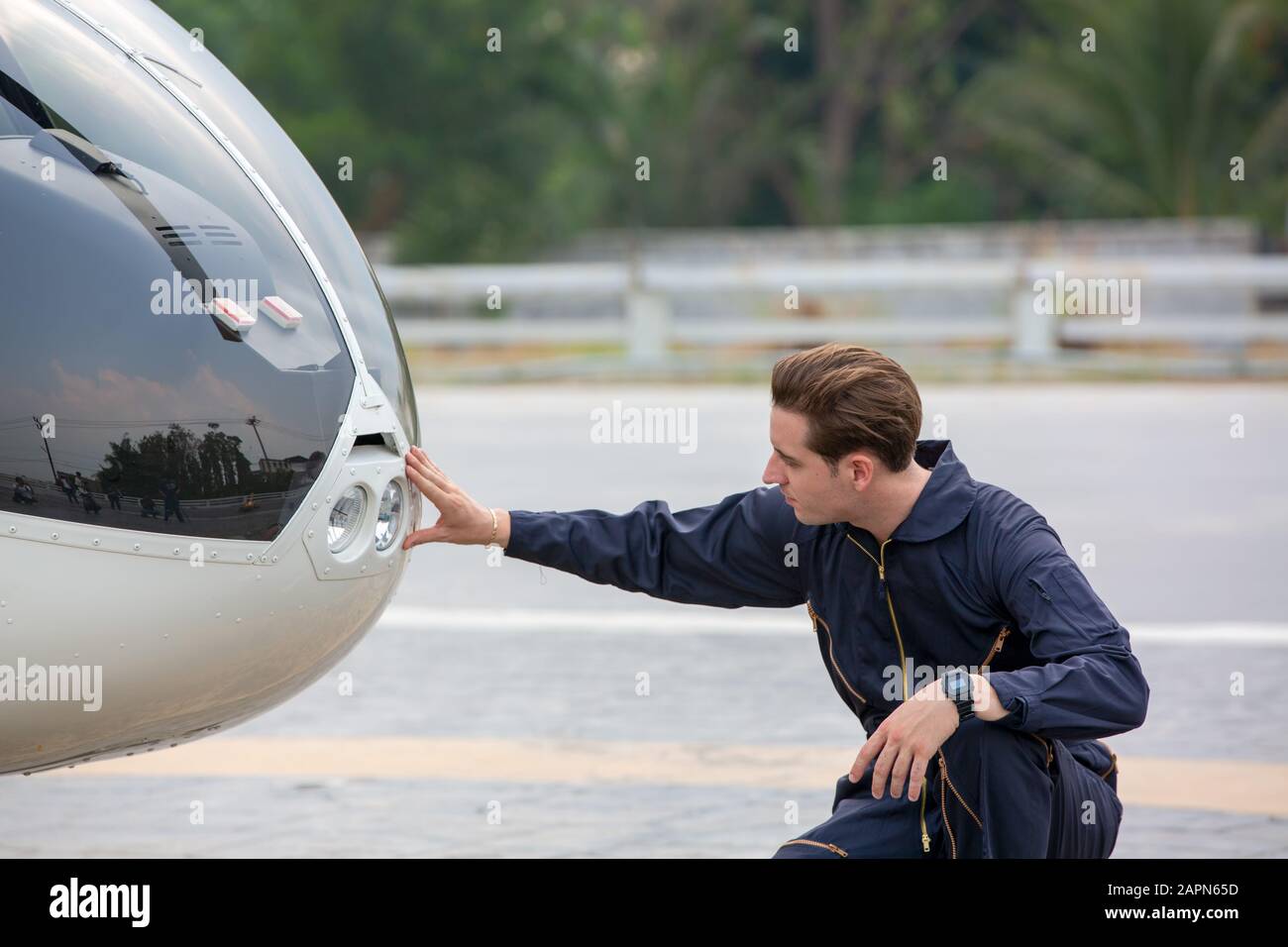 Commercial man pilot in technician suit standing in front of helicopter ...