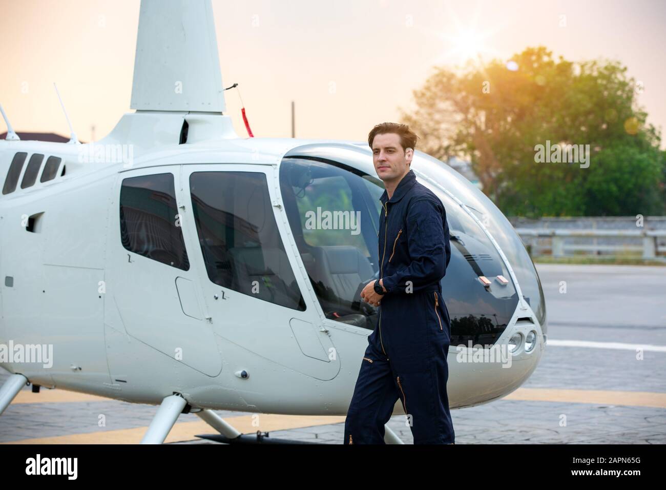 Commercial man pilot in technician suit standing in front of helicopter ...