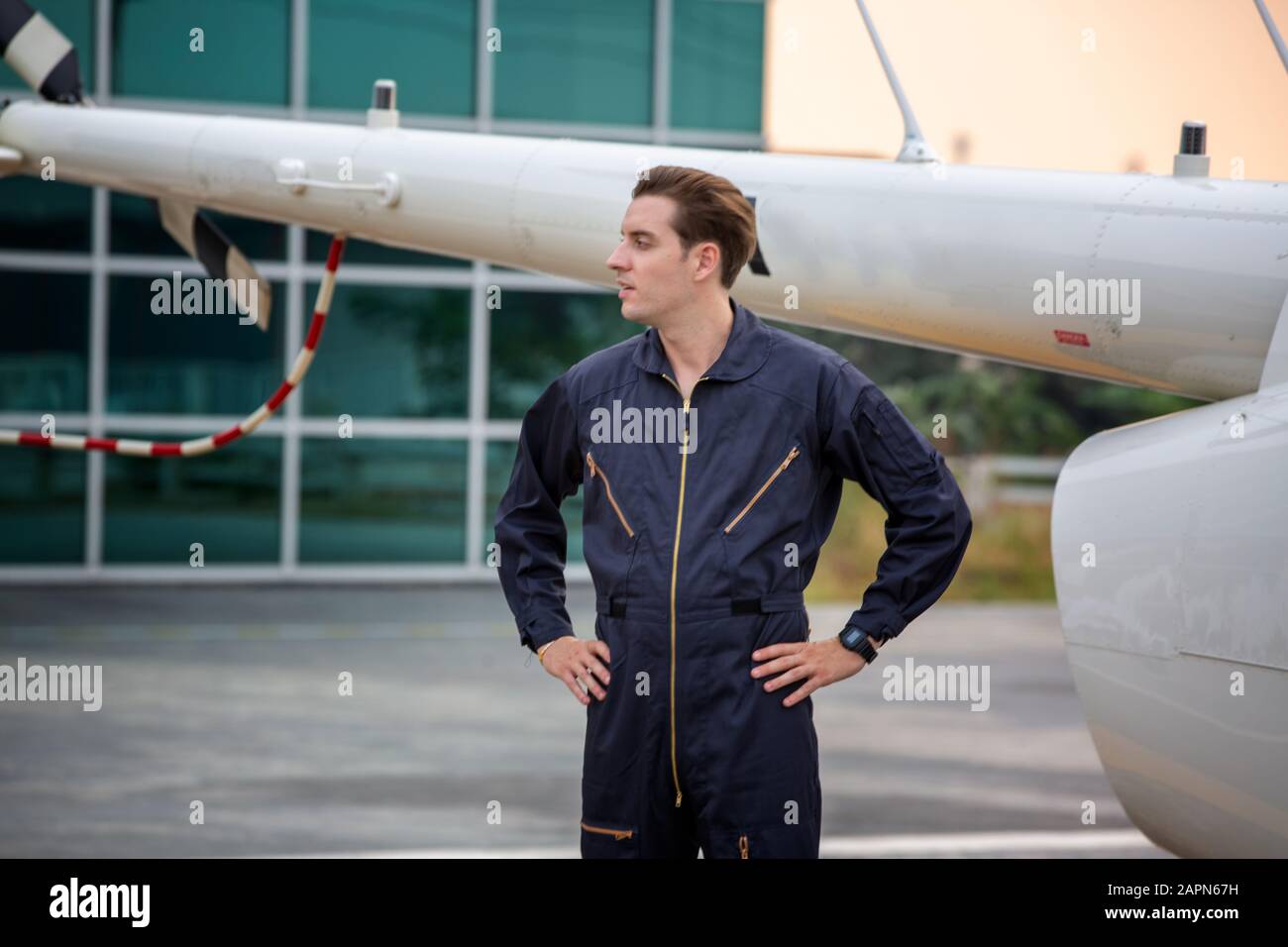 Commercial man pilot in technician suit standing in front of helicopter ...