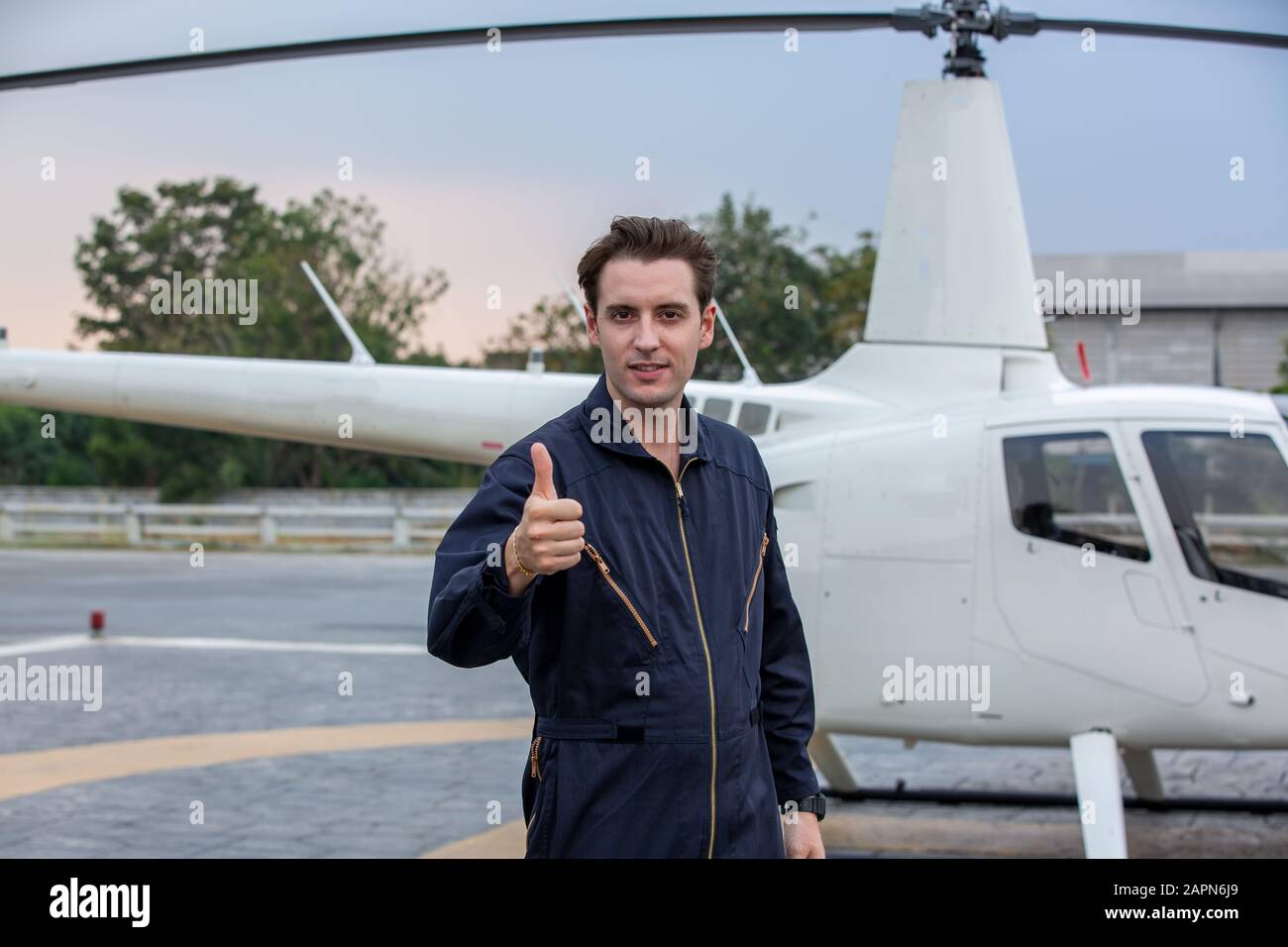 Commercial man pilot in technician suit standing in front of helicopter ...