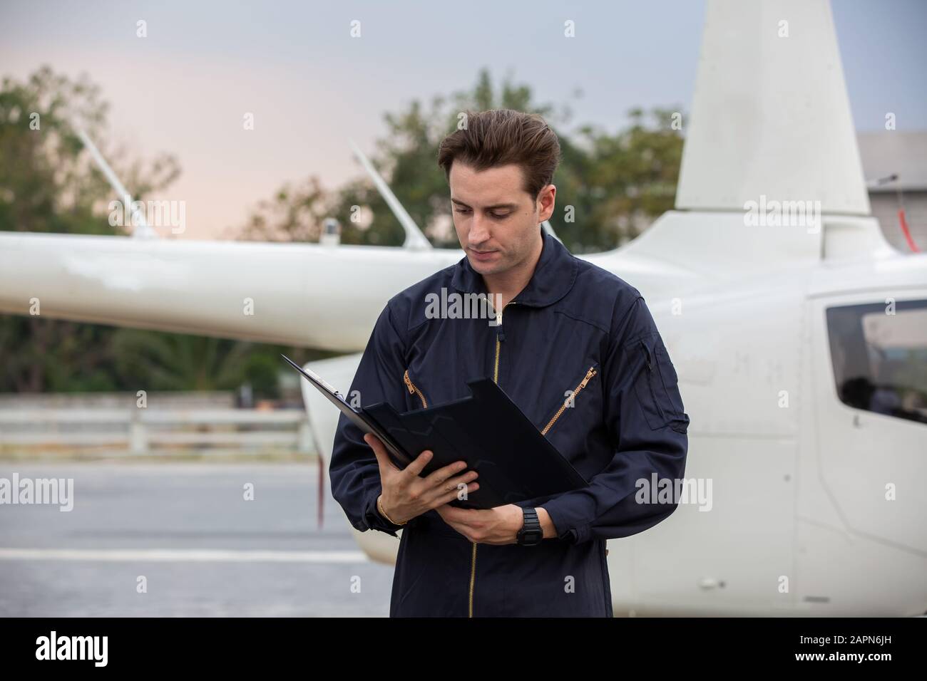Commercial man pilot in technician suit standing in front of helicopter ...