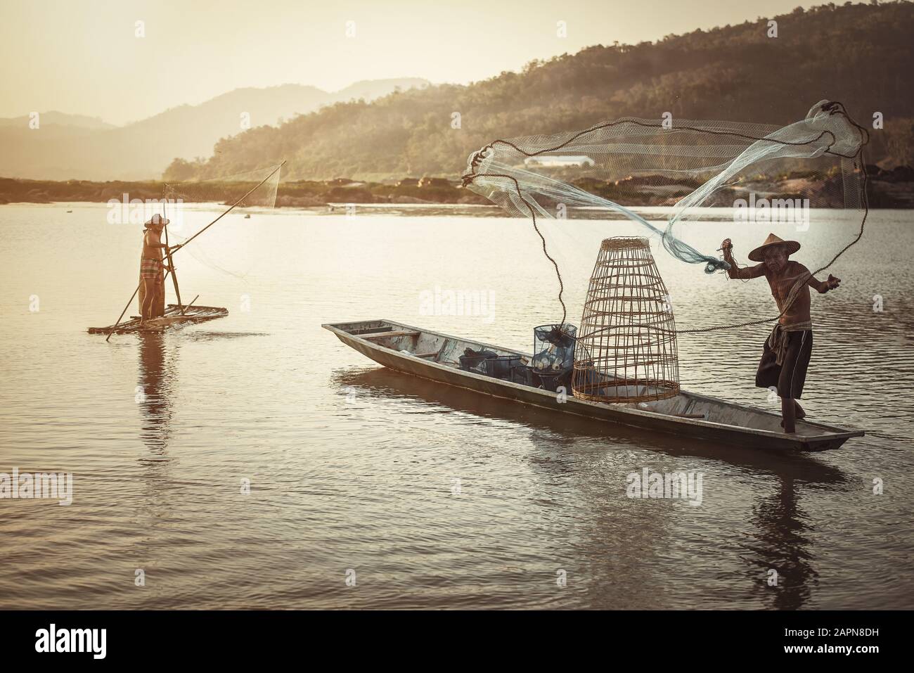 Thai fisherman on wooden boat casting a net for catching freshwater ...